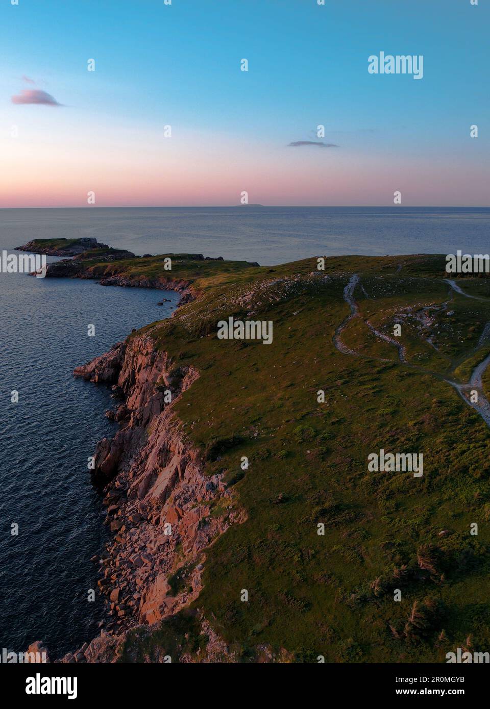 A scenic landscape of a cliff overlooking the ocean during sunrise ...