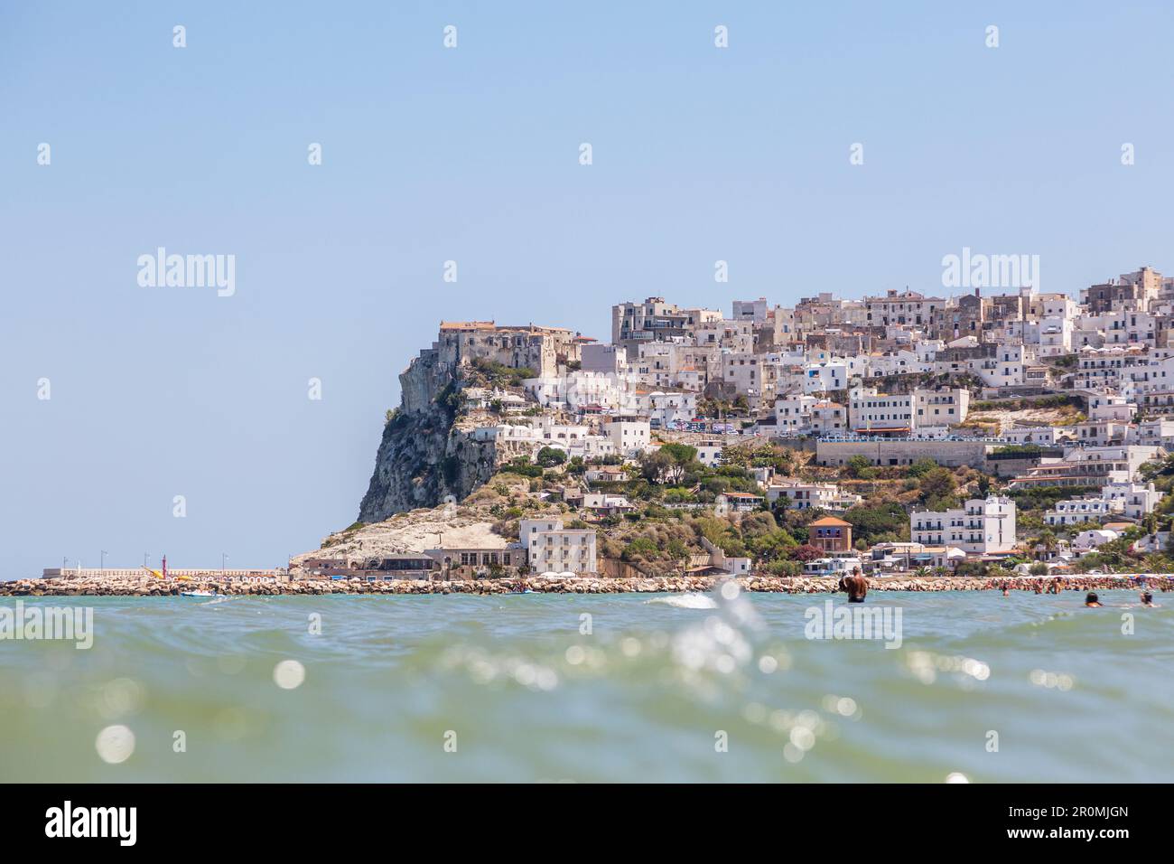 A sea beach with people who rest in the summer on it and buildings of ...