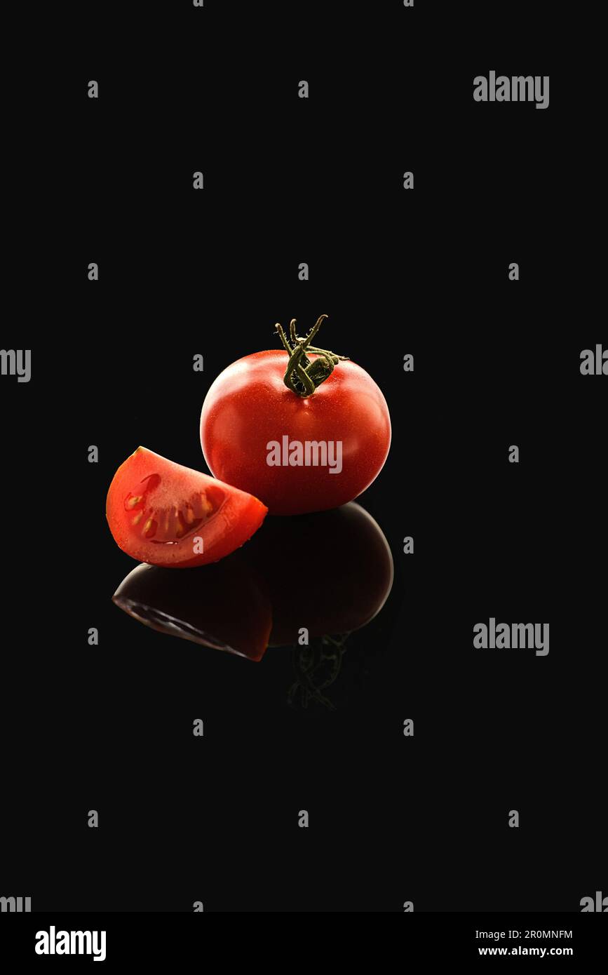 small tomato on the background with reflection with piece of tomato ...