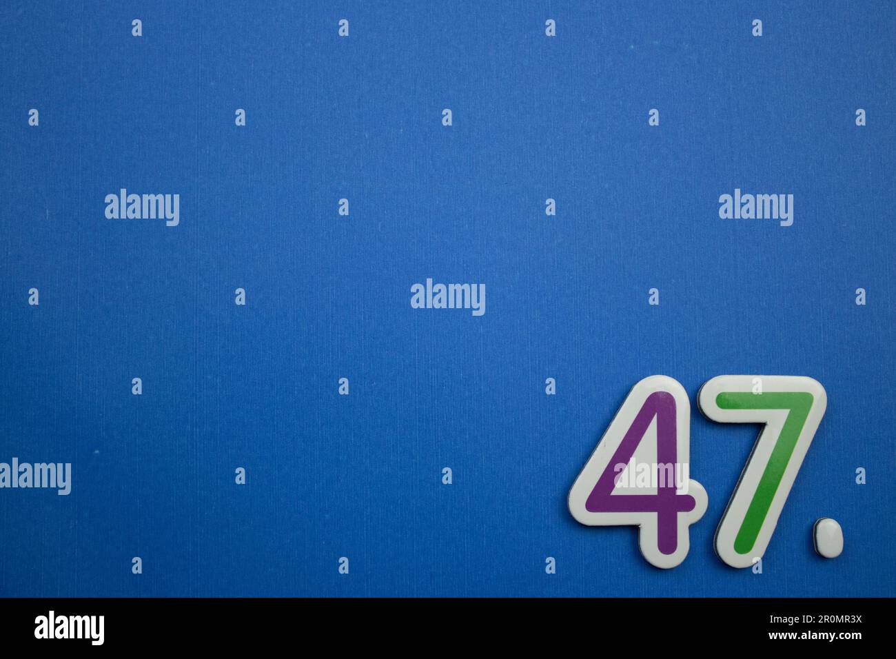 The number 47, placed on the edge of a blue background, photographed ...