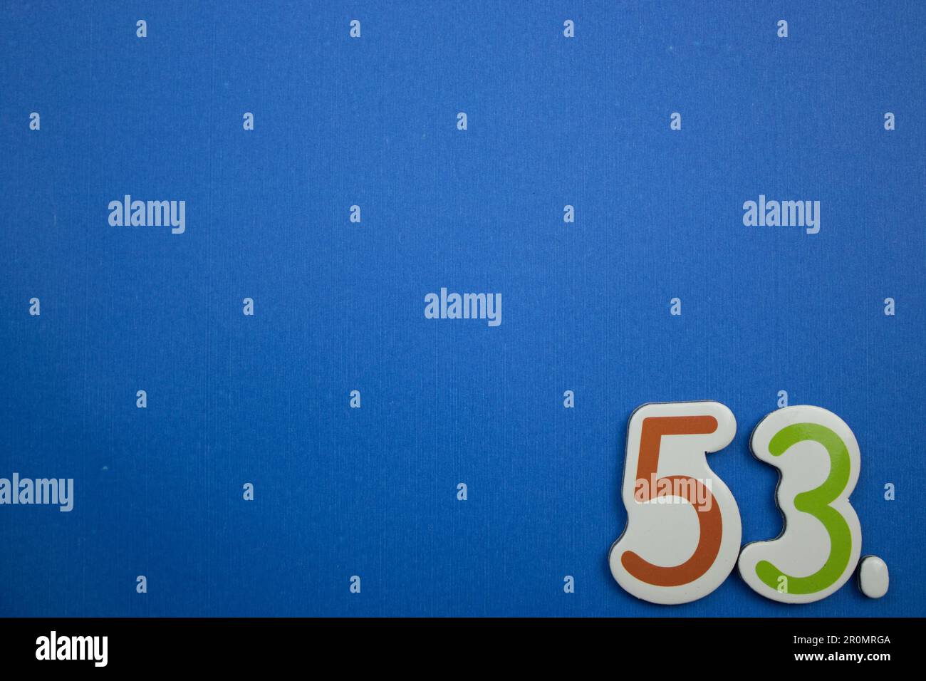 The number 53, placed on the edge of a blue background, photographed ...