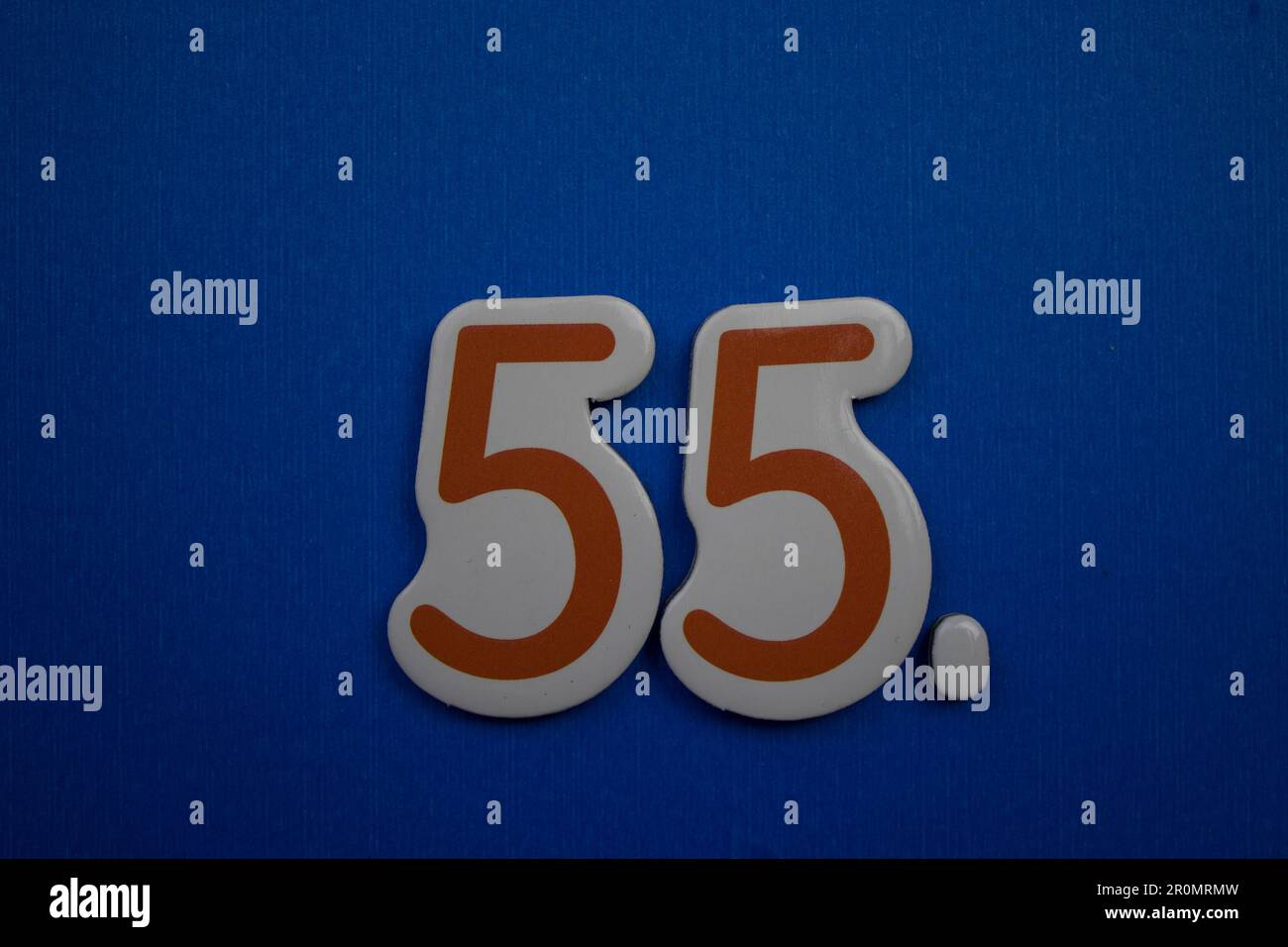 The number 55, placed on a blue background, photographed from above ...