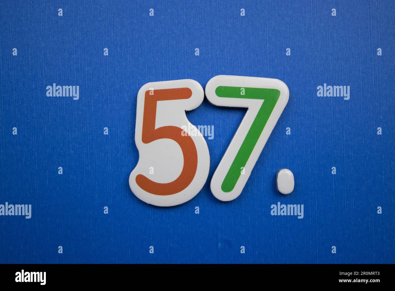 The number 57, placed on a blue background, photographed from above ...