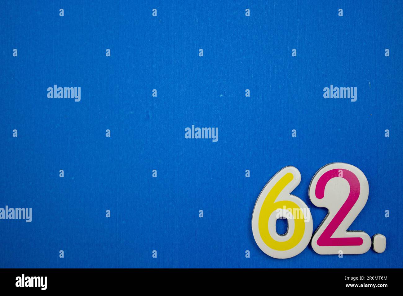The number 62, placed on the edge of a blue background, photographed ...