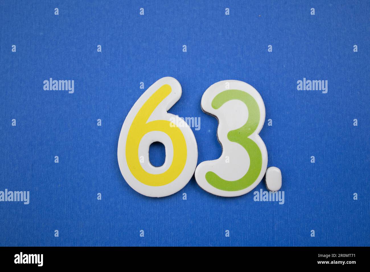 The number 63, placed on a blue background, photographed from above, colored yellow and green ...