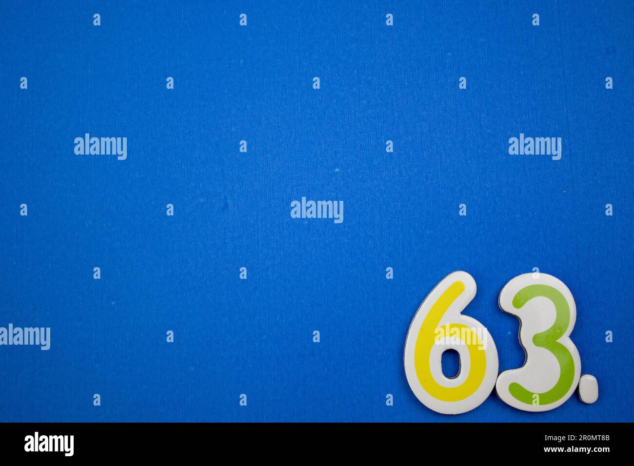 The number 63, placed on the edge of a blue background, photographed ...