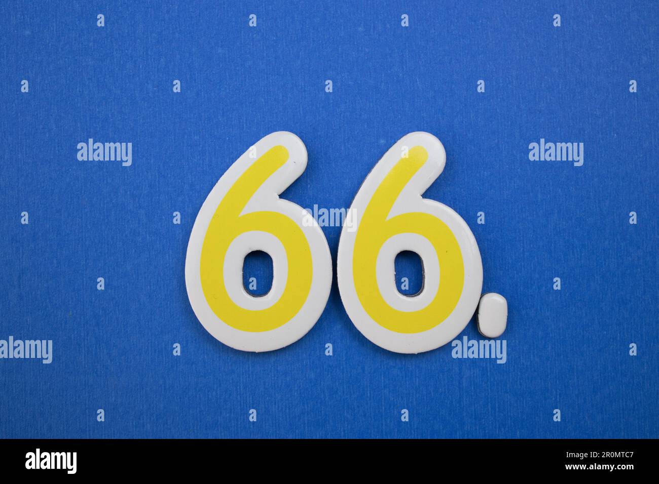 The number 66 in yellow, photographed from above, placed on a blue ...