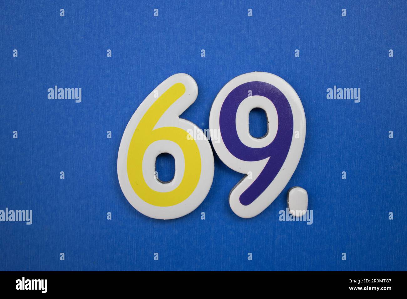 The number 69, placed on a blue background, photographed from above, colored yellow and purple ...