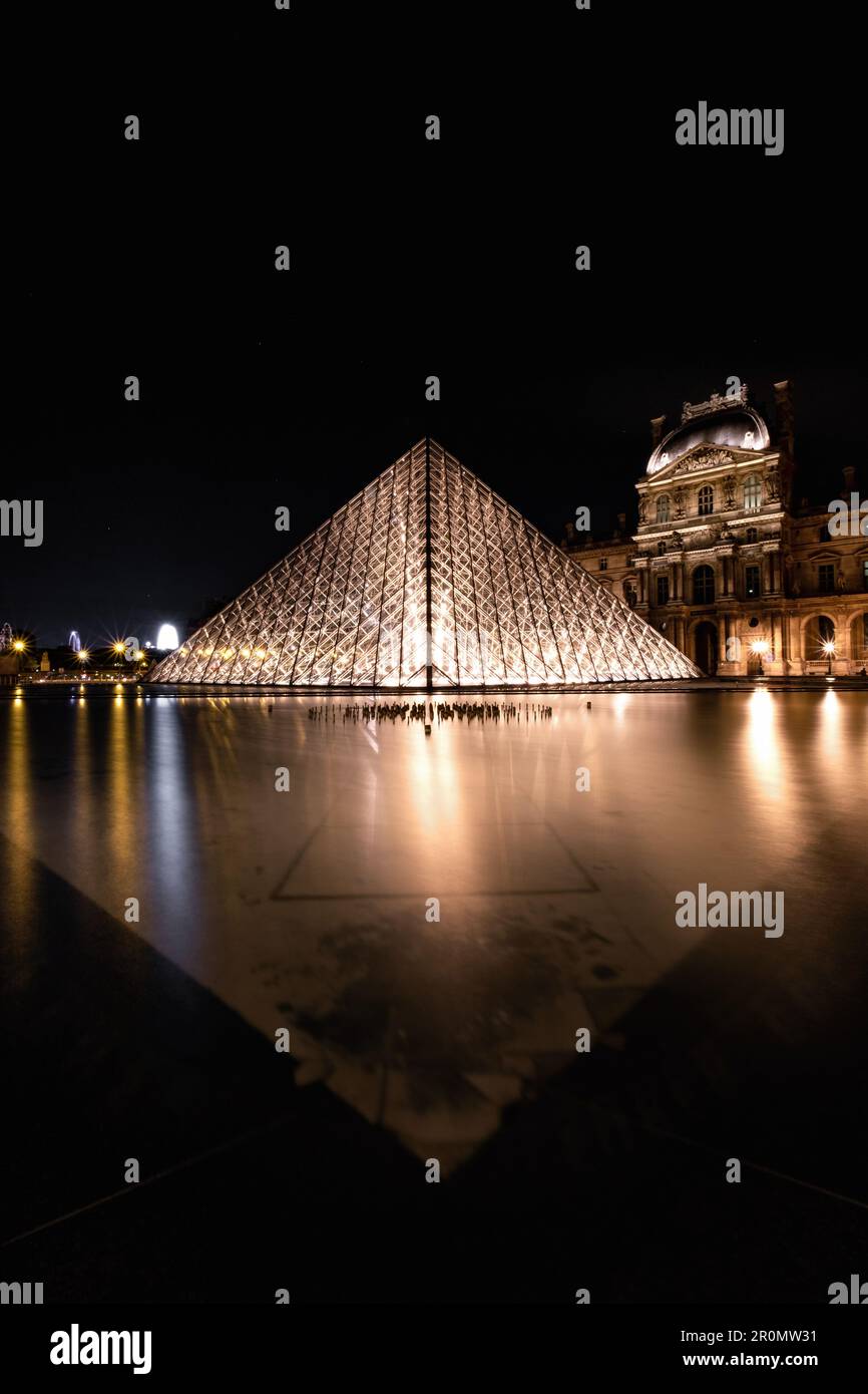 Illuminated pyramid in the Louvre at night, light reflections in the ...