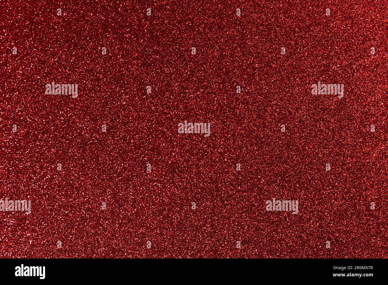 A vibrant red glitter fabric background with subtle shimmering light effects, creating a ...