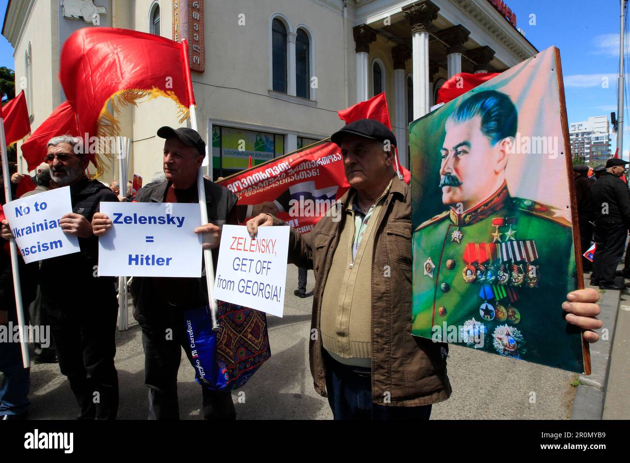 Elderly people with red flags hold a portrait of a Soviet leader Josef ...