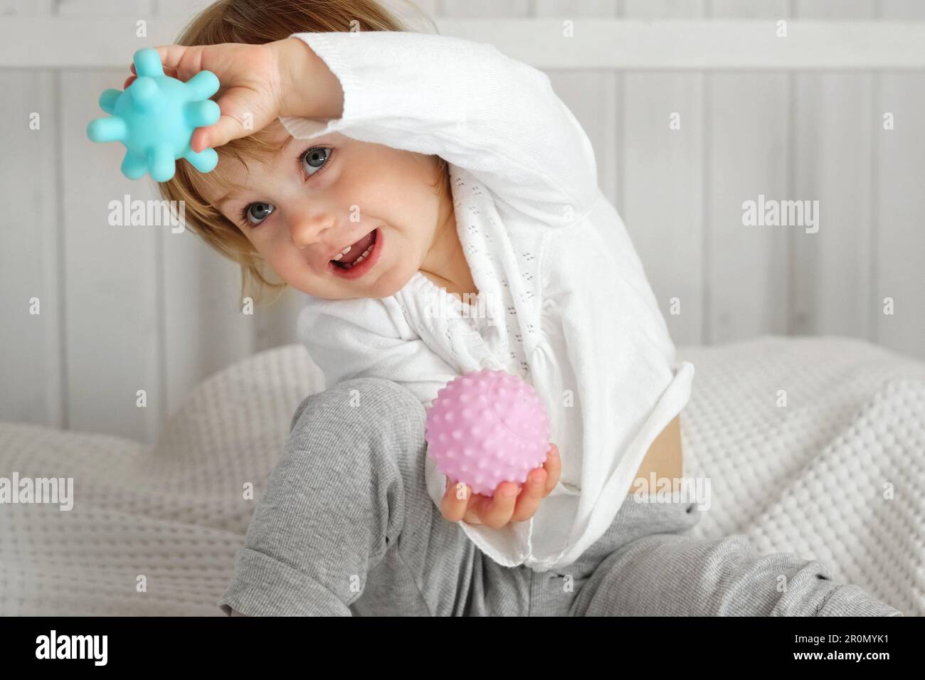 Cute baby girl playing tactile knobby balls. Young child hand plays ...