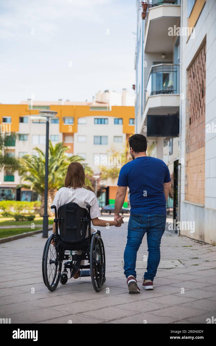 Back view of full body of cheerful husband with disabled wife in ...