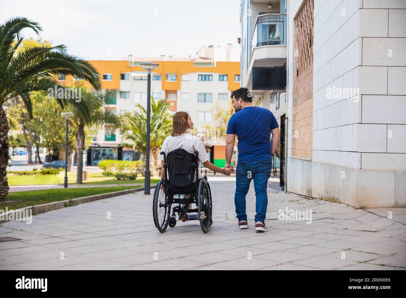 Back view of full body of cheerful husband with disabled wife in ...