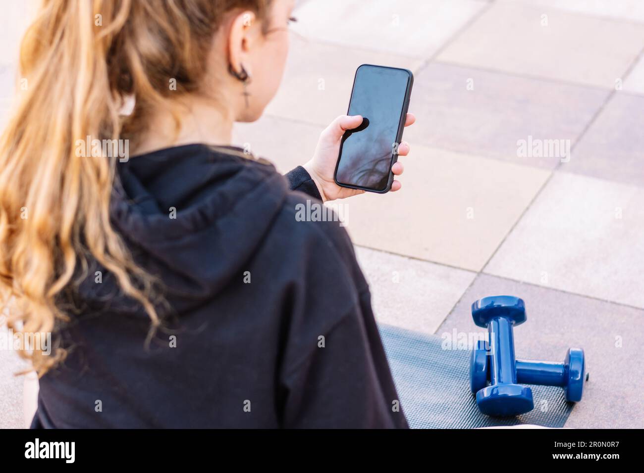 From above back view of faceless woman in sportswear browsing ...