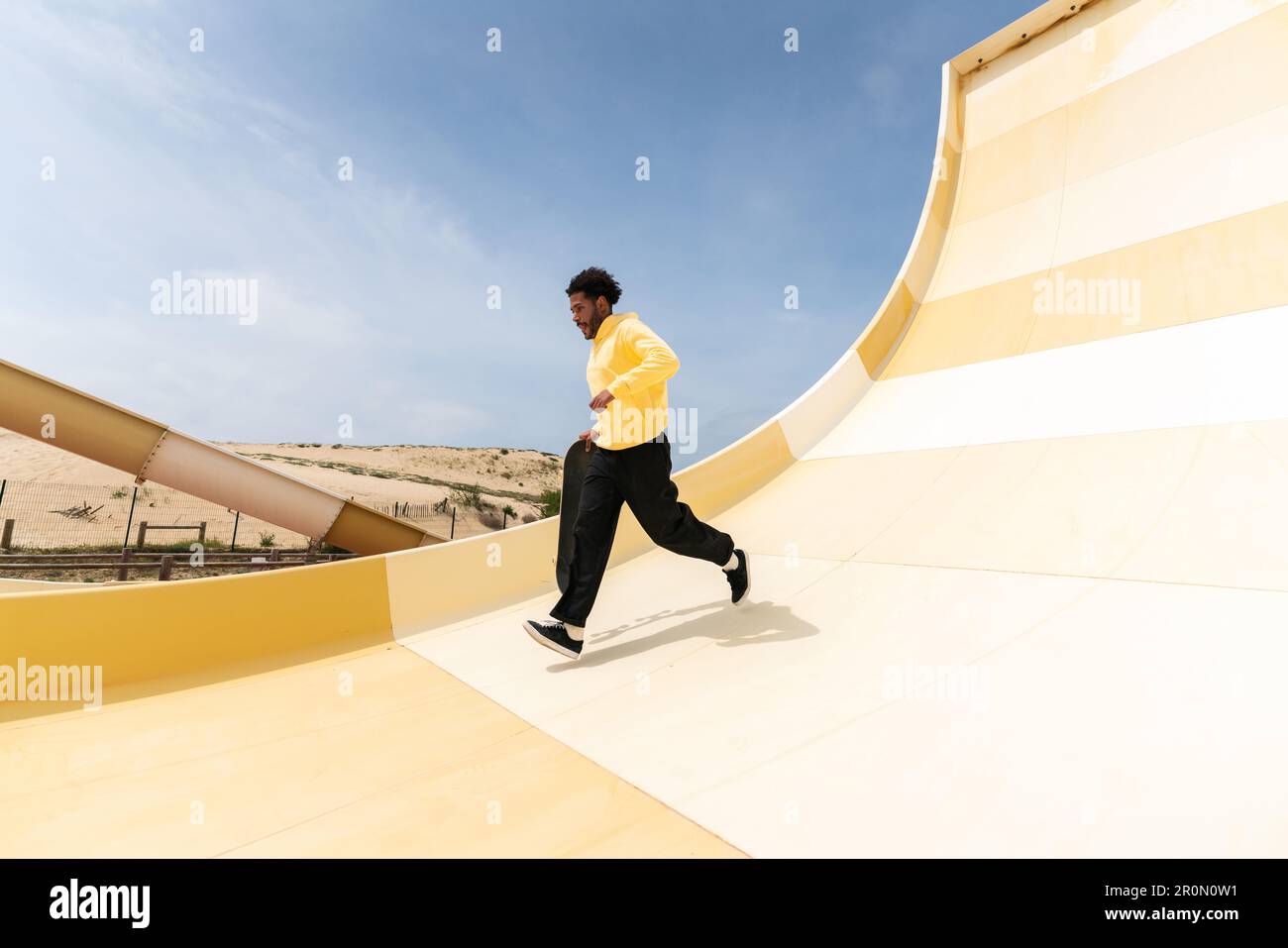 Full body side view of African American male skater in casual clothes ...
