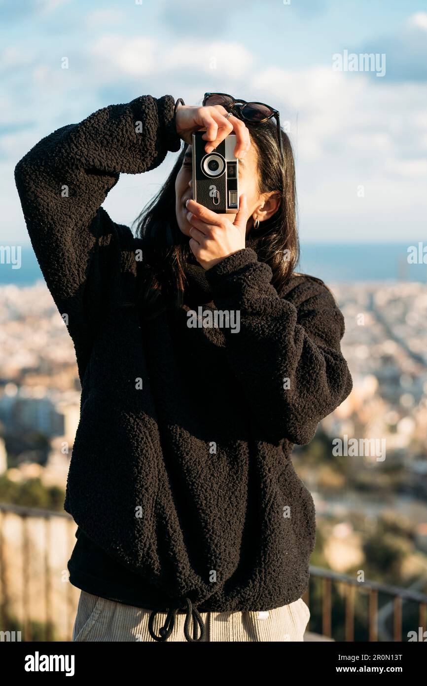 Anonymous female photographer in black hoodie taking picture on vintage ...