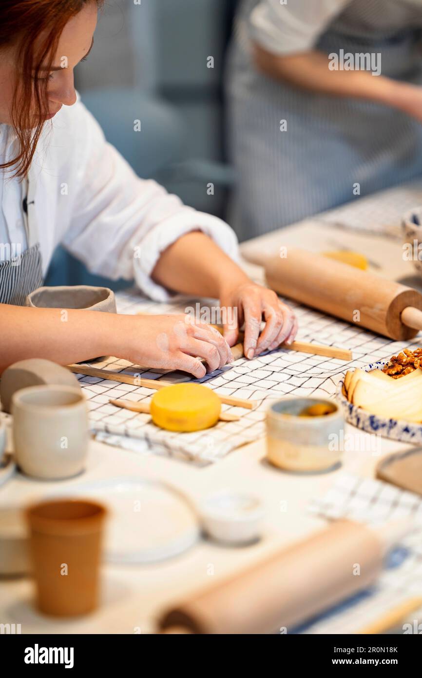 Anonymous female artisan using wooden sticks to make straight clay ...
