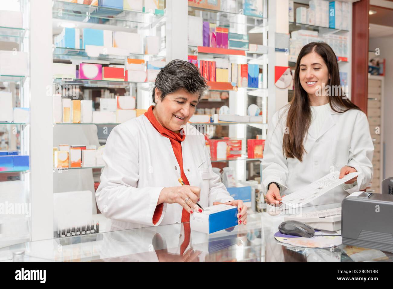 Pharmacist in medical uniform using utility knife while opening box of ...