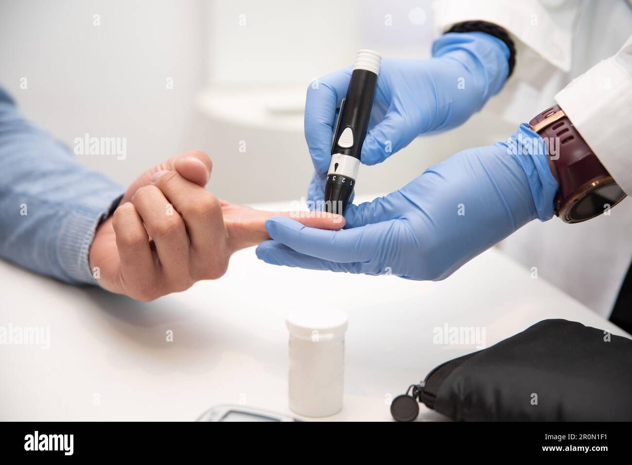 Faceless medical worker in gloves using microlet next lancing device ...