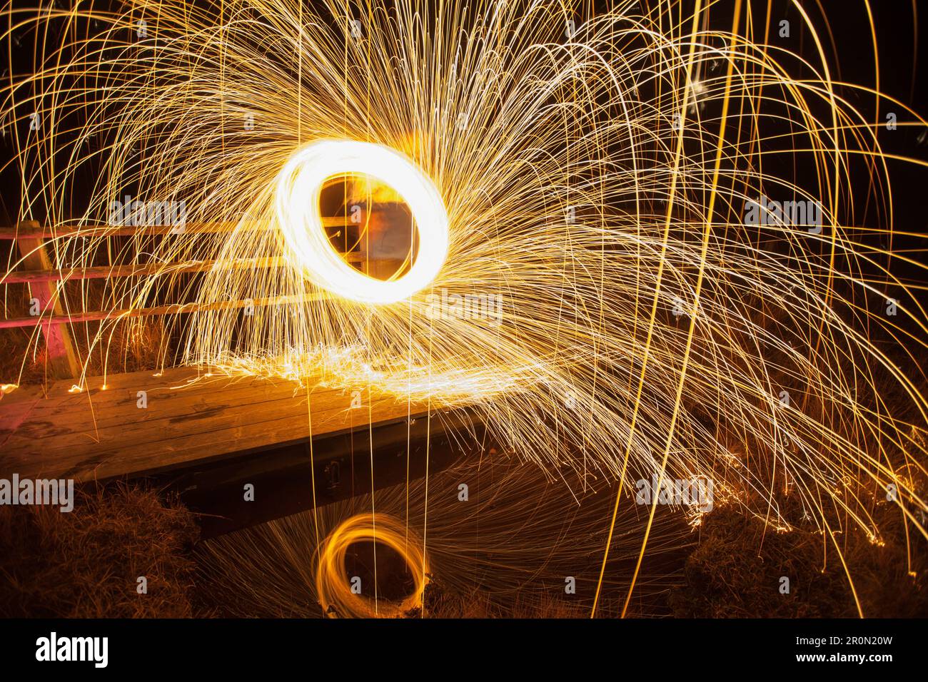Back view of man standing in dark park with bright flames with long exposure effect Stock Photo ...