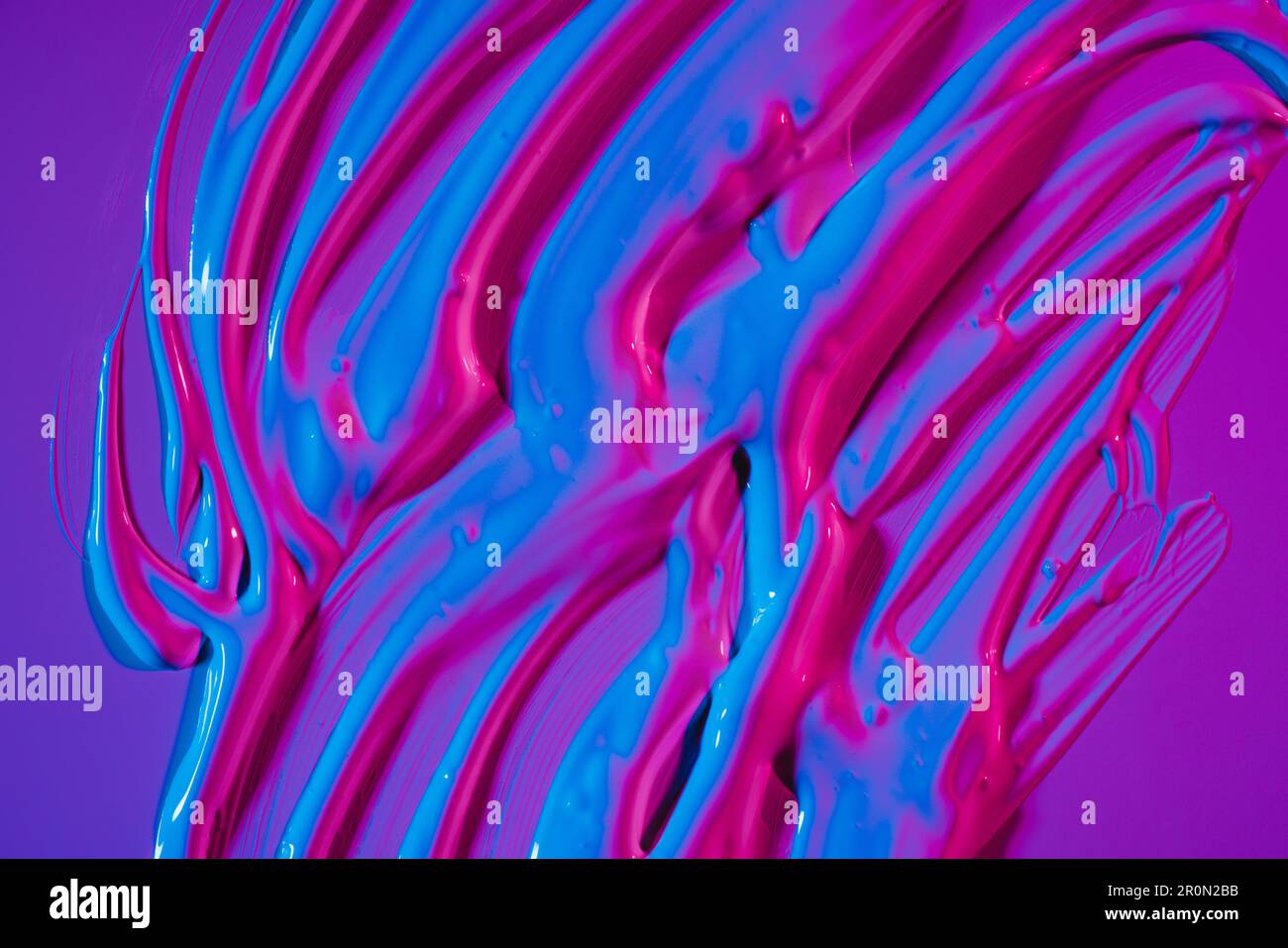 From above puddle of bright neon acrylic paint spread on vivid purple ...