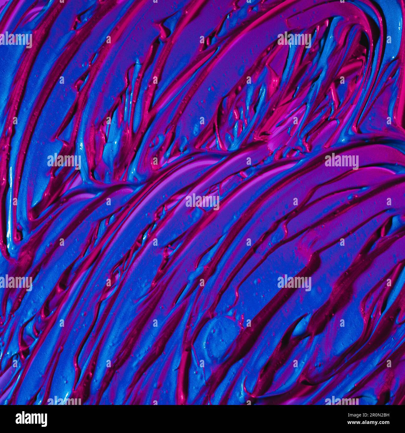 From above puddle of bright neon acrylic paint spread on vivid purple ...