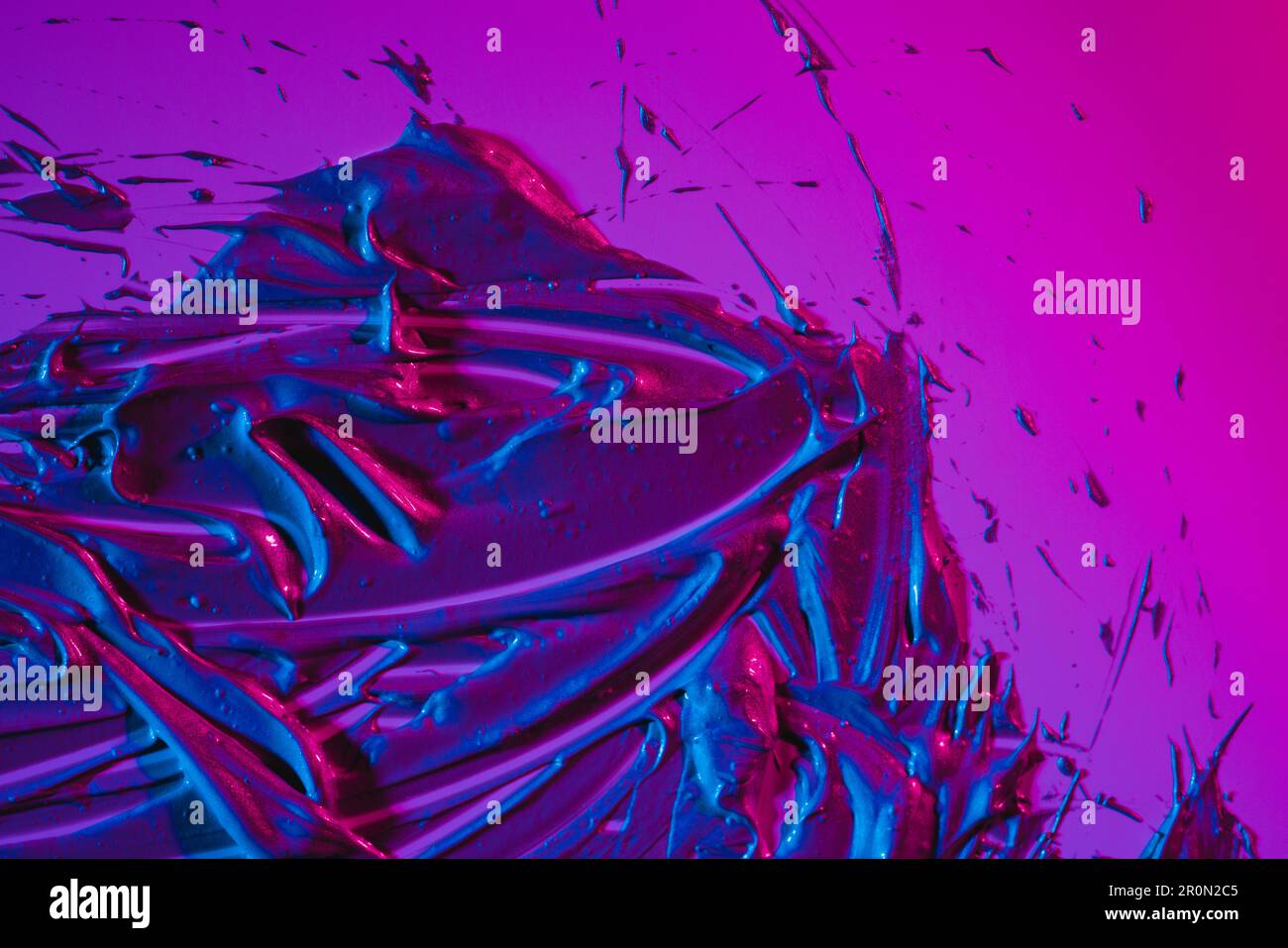 From above puddle of bright neon acrylic paint spread on vivid purple ...