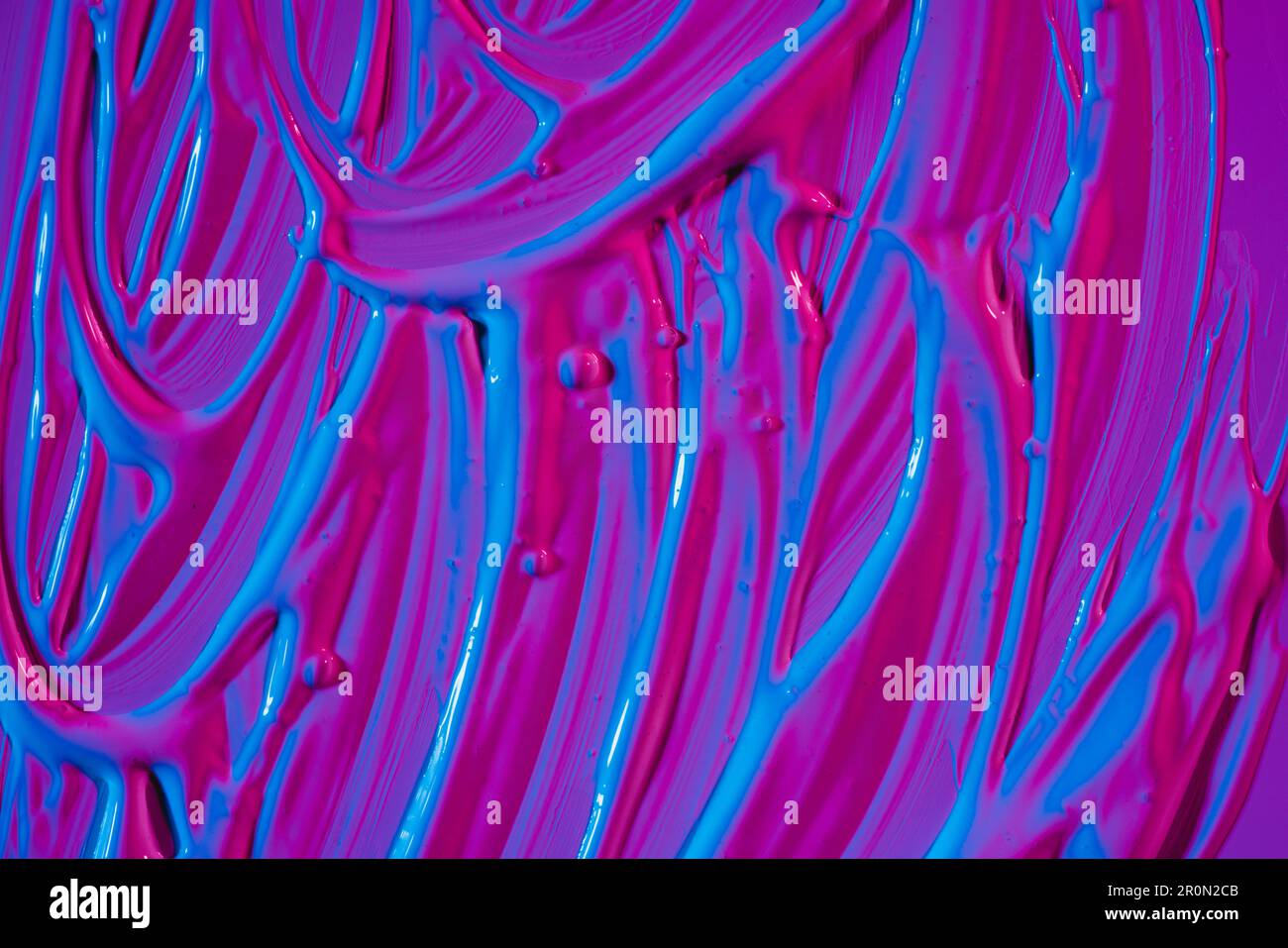 From above puddle of bright neon acrylic paint spread on vivid purple ...