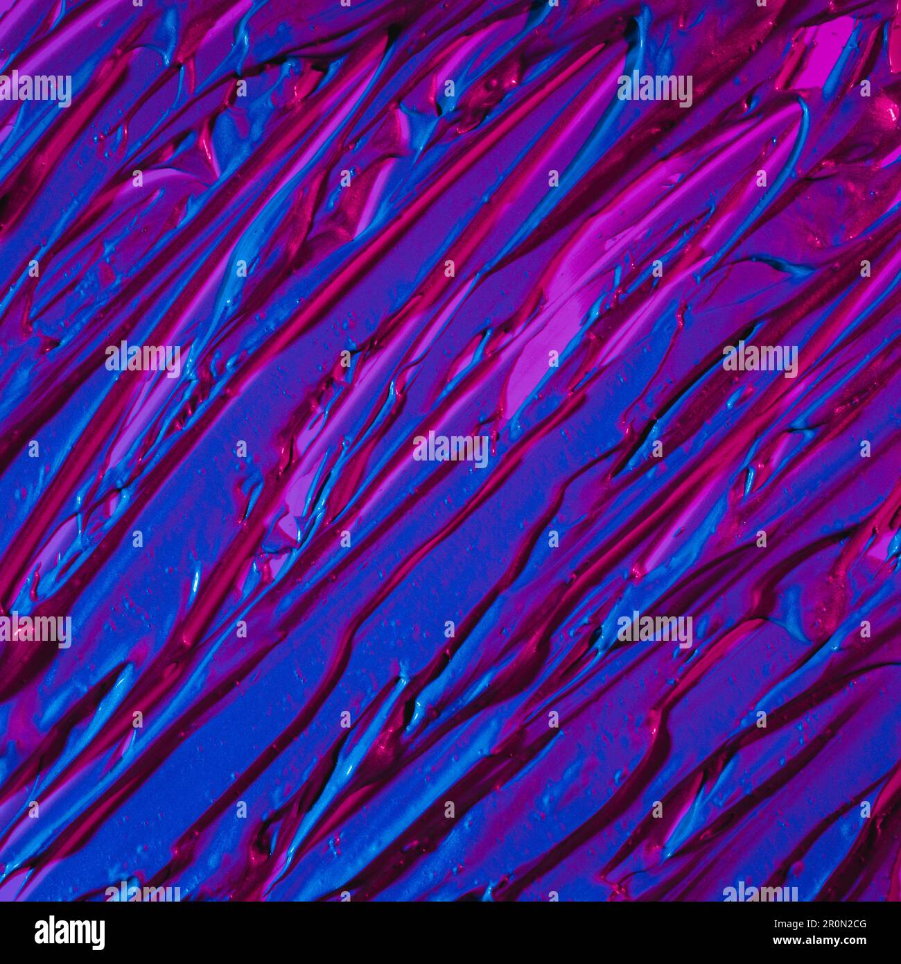 From above puddle of bright neon acrylic paint spread on vivid purple ...