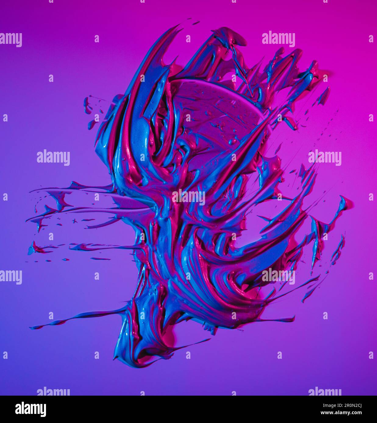 From above puddle of bright neon acrylic paint spread on vivid purple ...