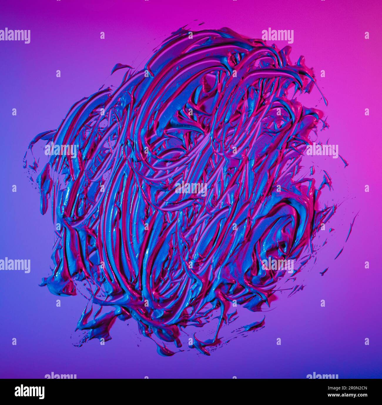 From above puddle of bright neon acrylic paint spread on vivid purple ...