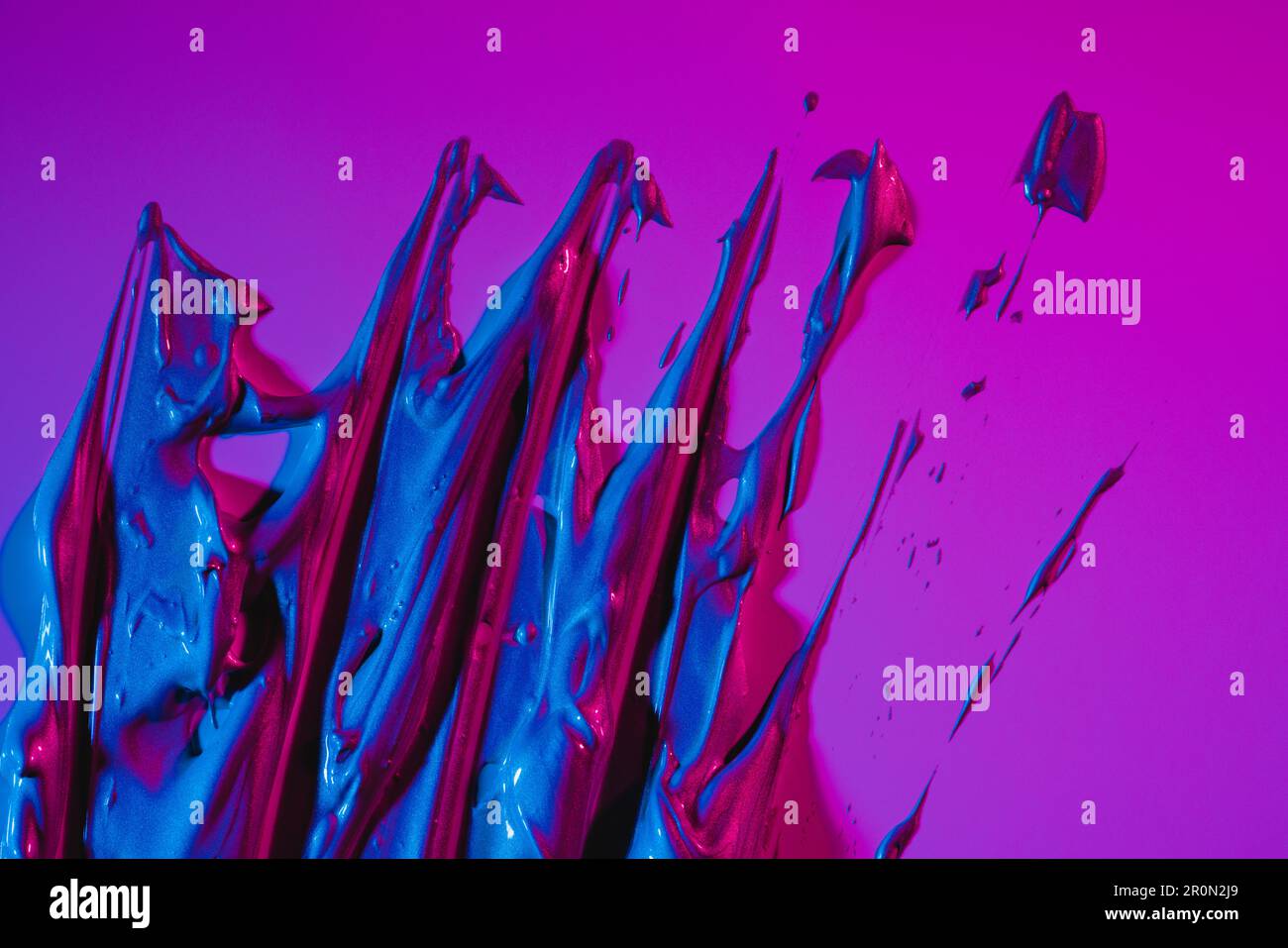 From above puddle of bright neon acrylic paint spread on vivid purple ...