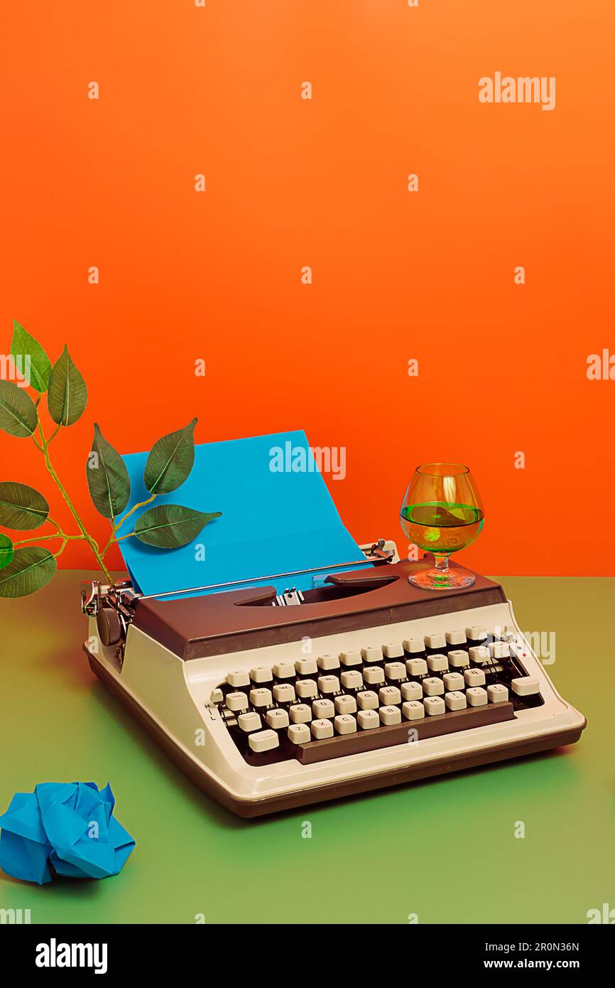 High angle of vintage typewriter with green leaves and crumpled blue ...