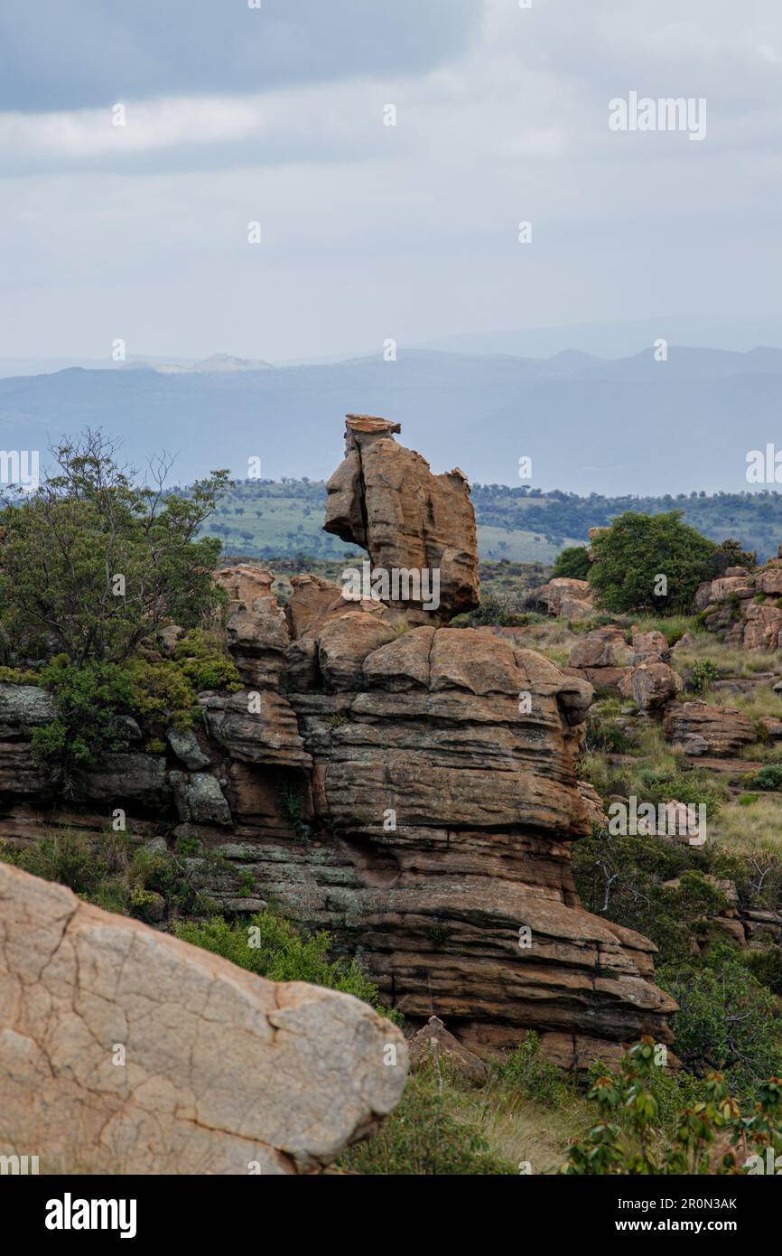 A scenic outdoor landscape featuring a rocky outcrop near a tranquil ...