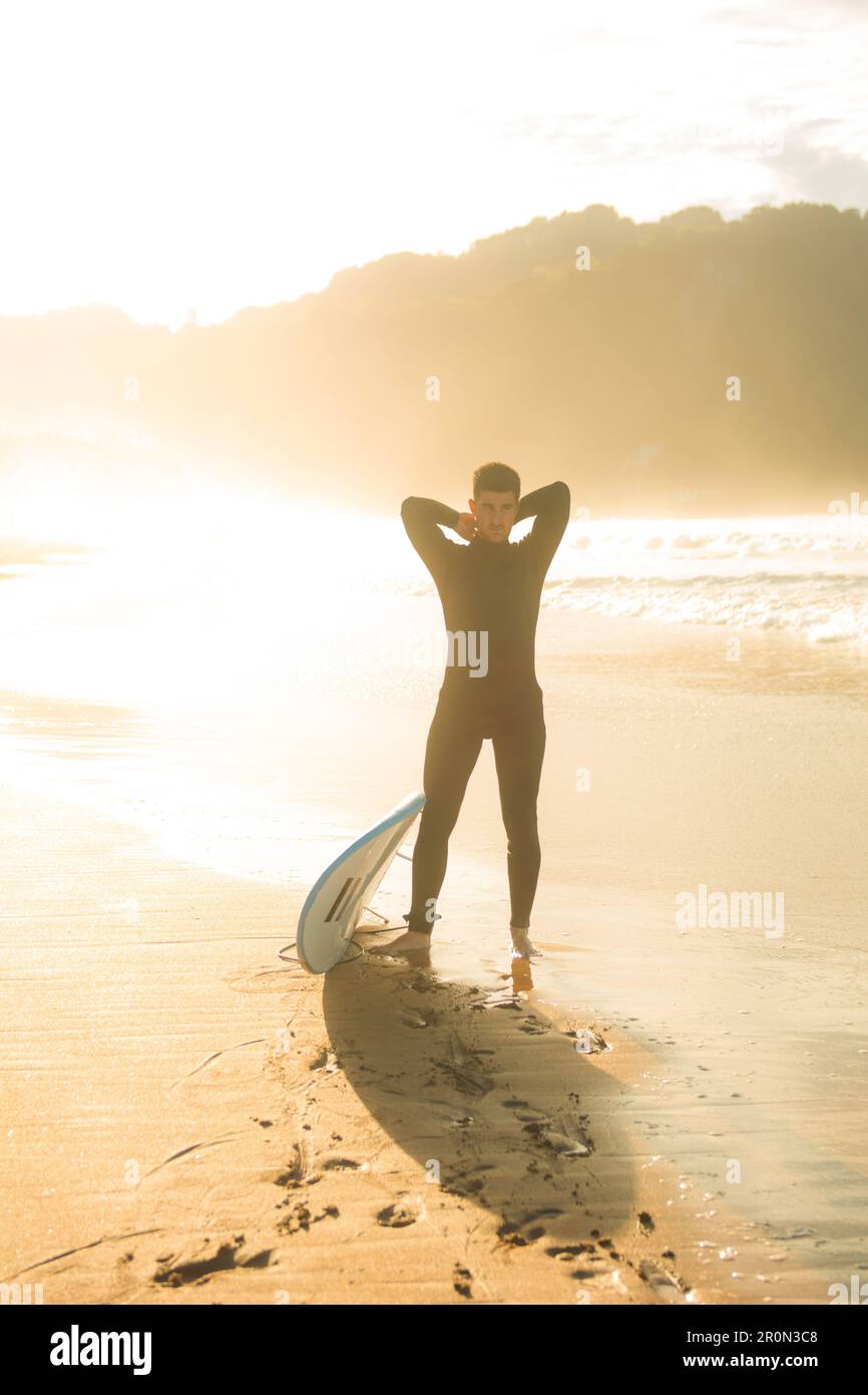 Full body of young male surfer in swimsuit standing barefoot on sandy ...