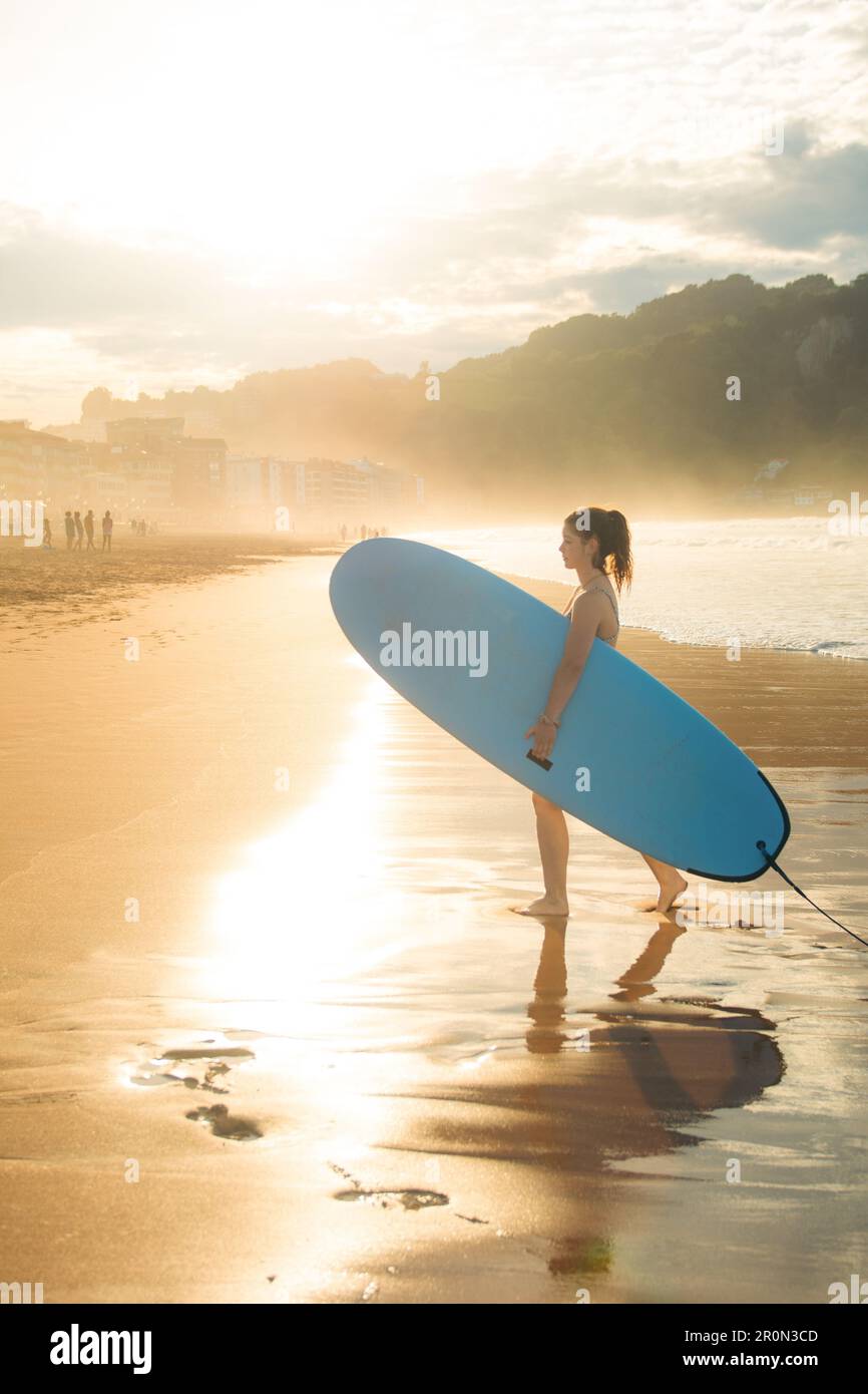 Full body of female surfer in swimsuit walking with surfboard and ...