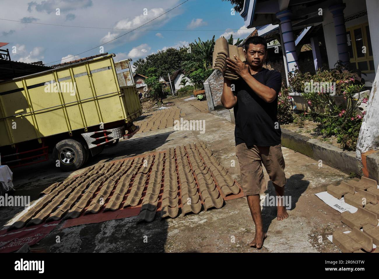 A craftsman carries tiles on his back at the tile industry center in ...