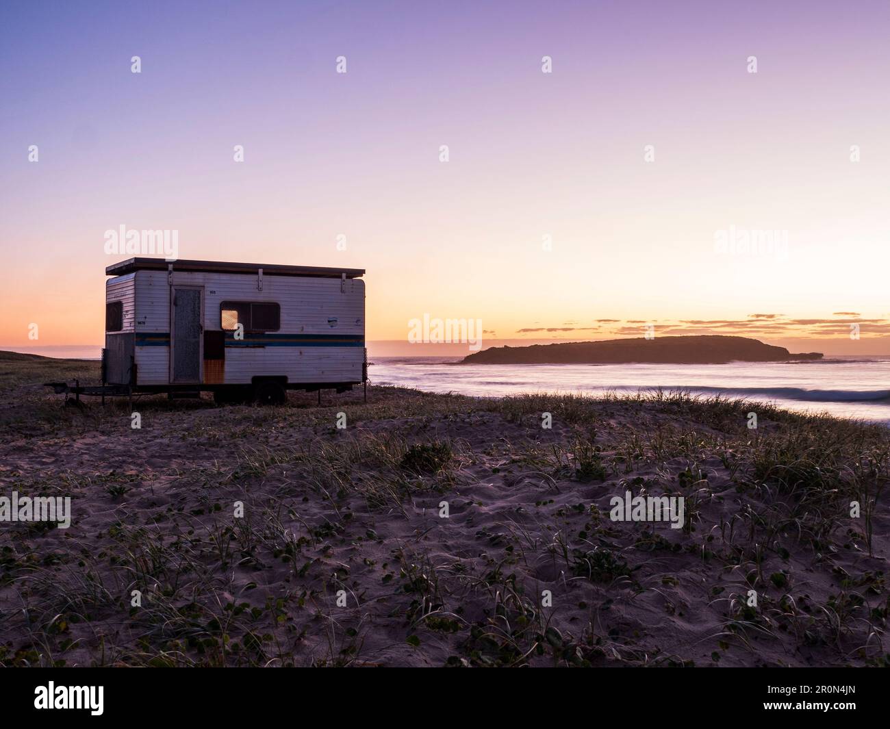 A trailer parked on a sandy beach at the ocean at sunset Stock Photo ...
