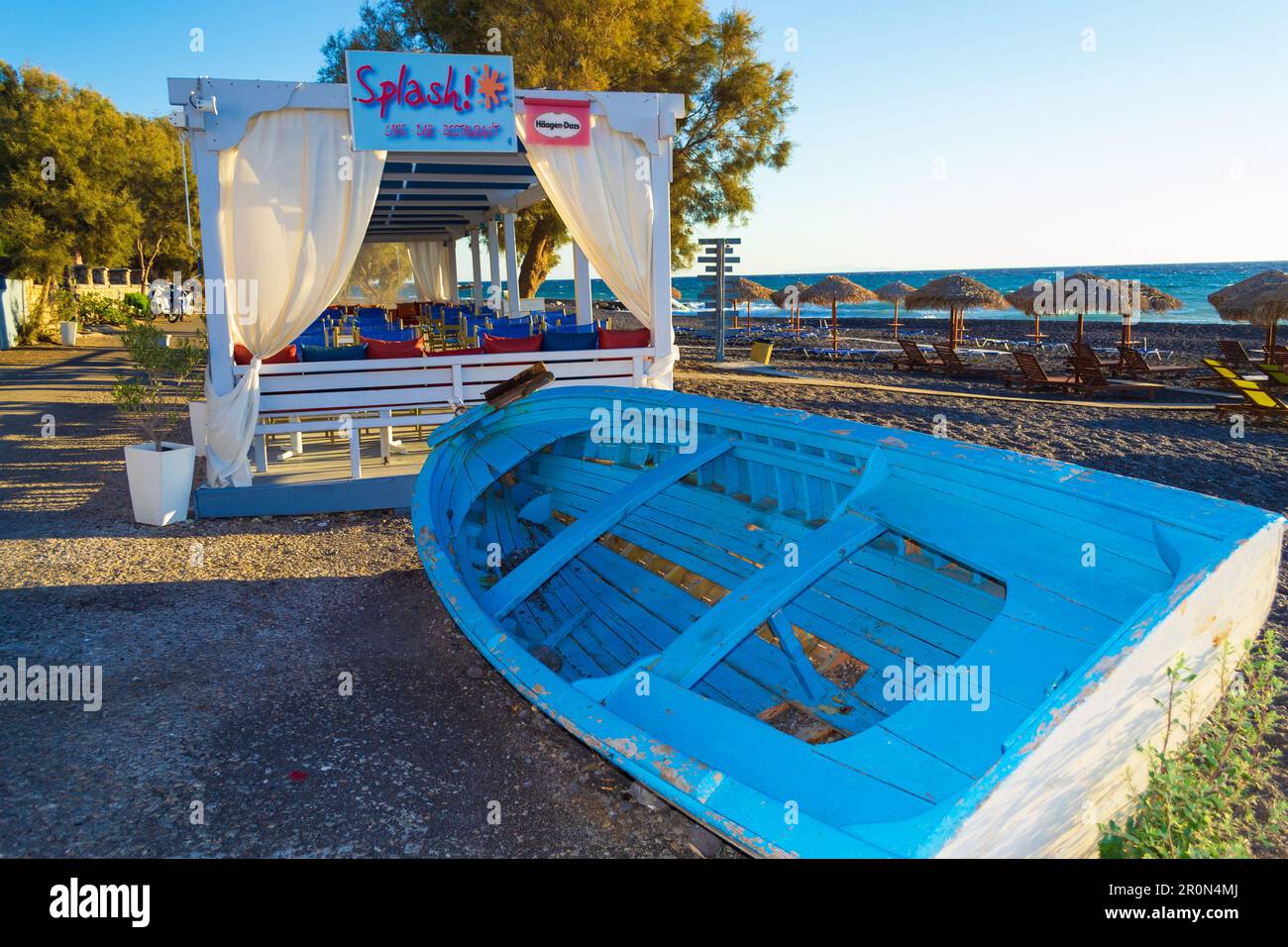 Old boat and restaurant outdoor seating at Kamari promenade overlooking ...