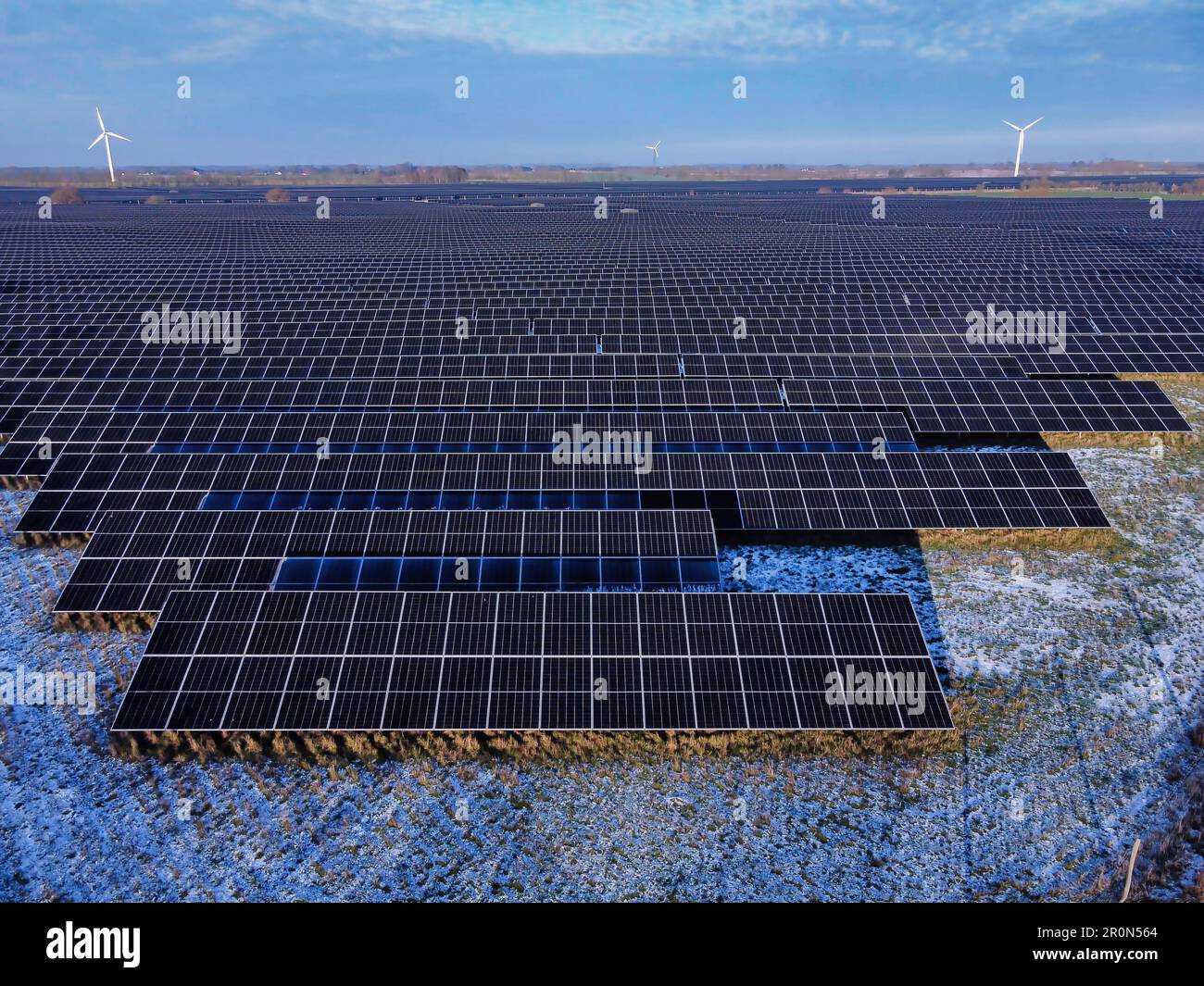 A top-down aerial view of a large field filled with solar panels, all ...