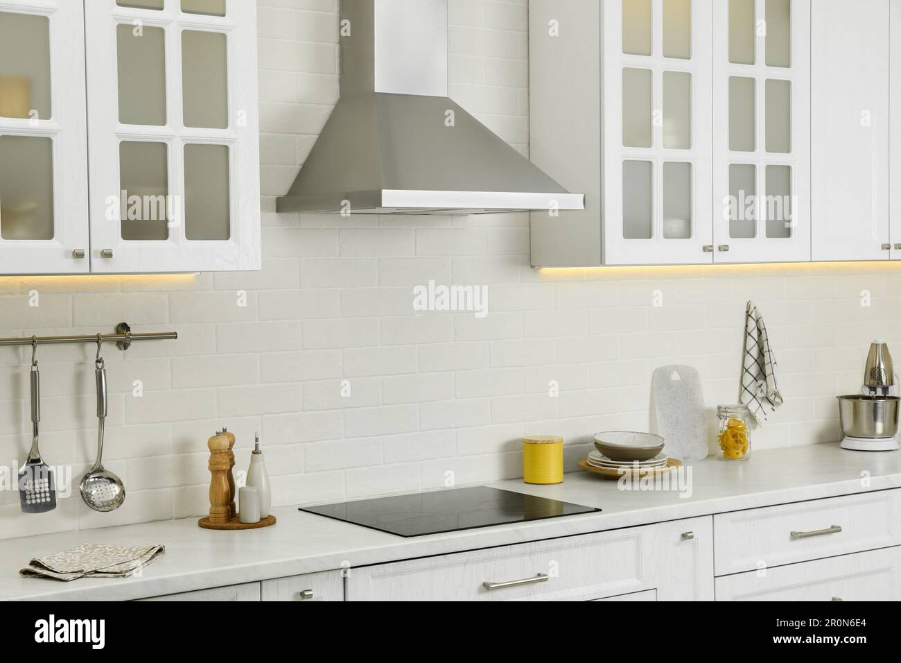 Elegant kitchen interior with modern range hood over cooktop and ...