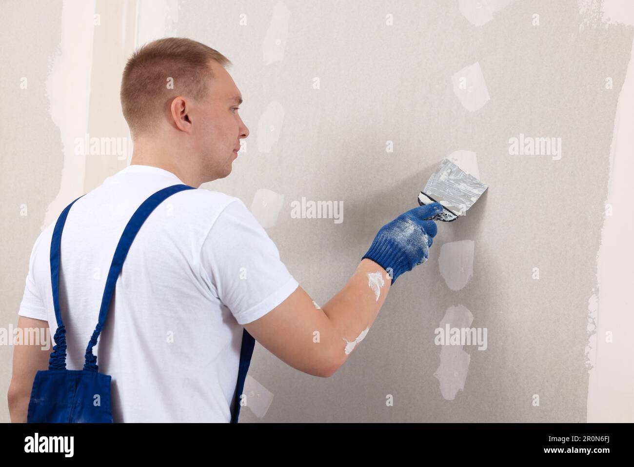 Man plastering wall with putty knife indoors. Home renovation Stock ...