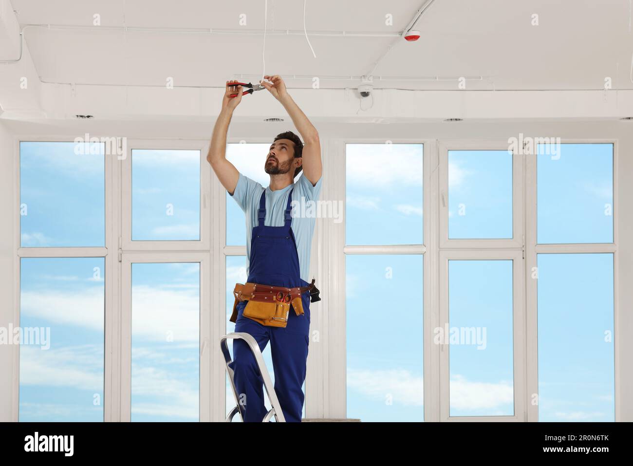 Electrician with pliers repairing ceiling wiring indoors Stock Photo ...