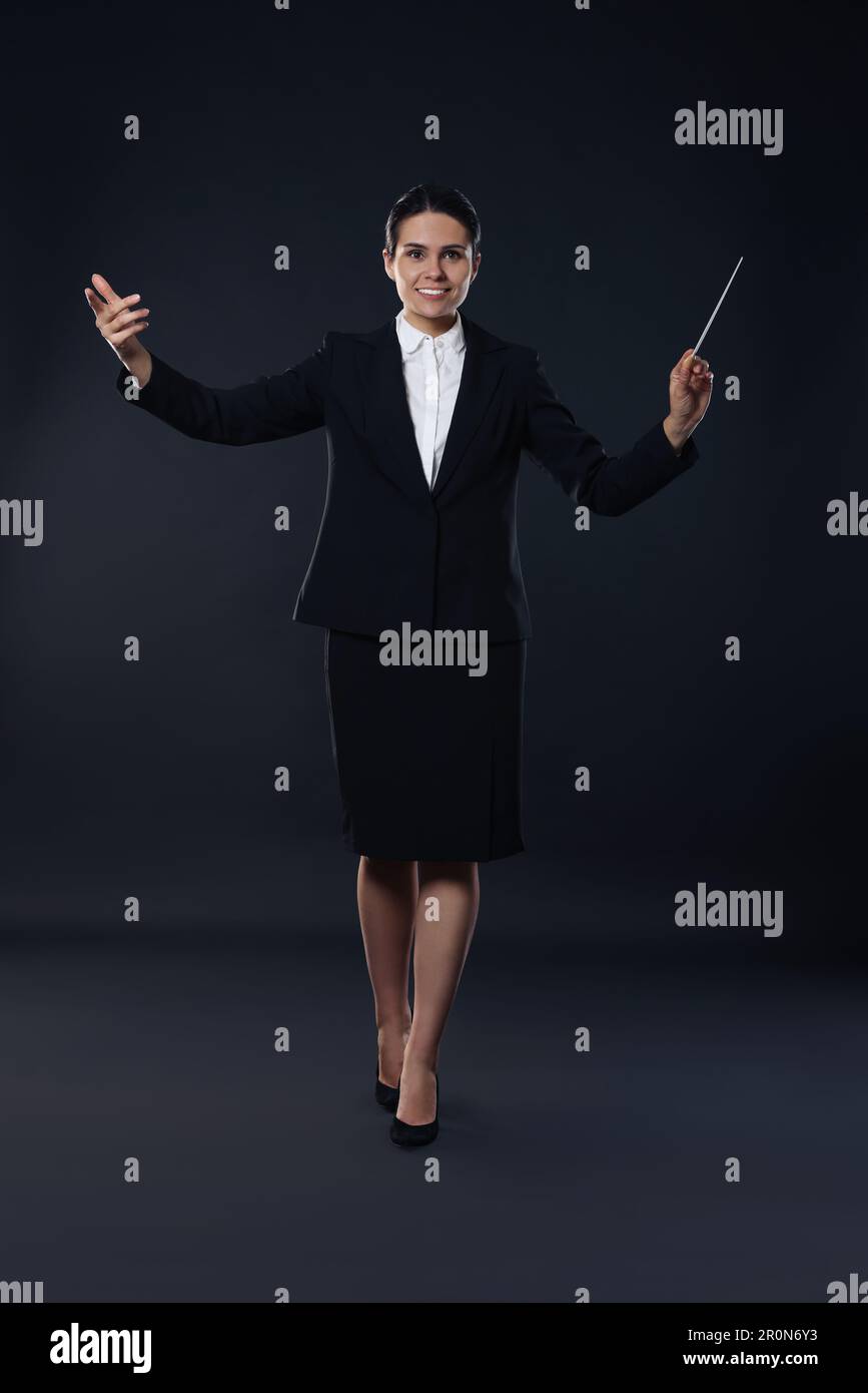 Happy young conductor with baton on dark background Stock Photo - Alamy