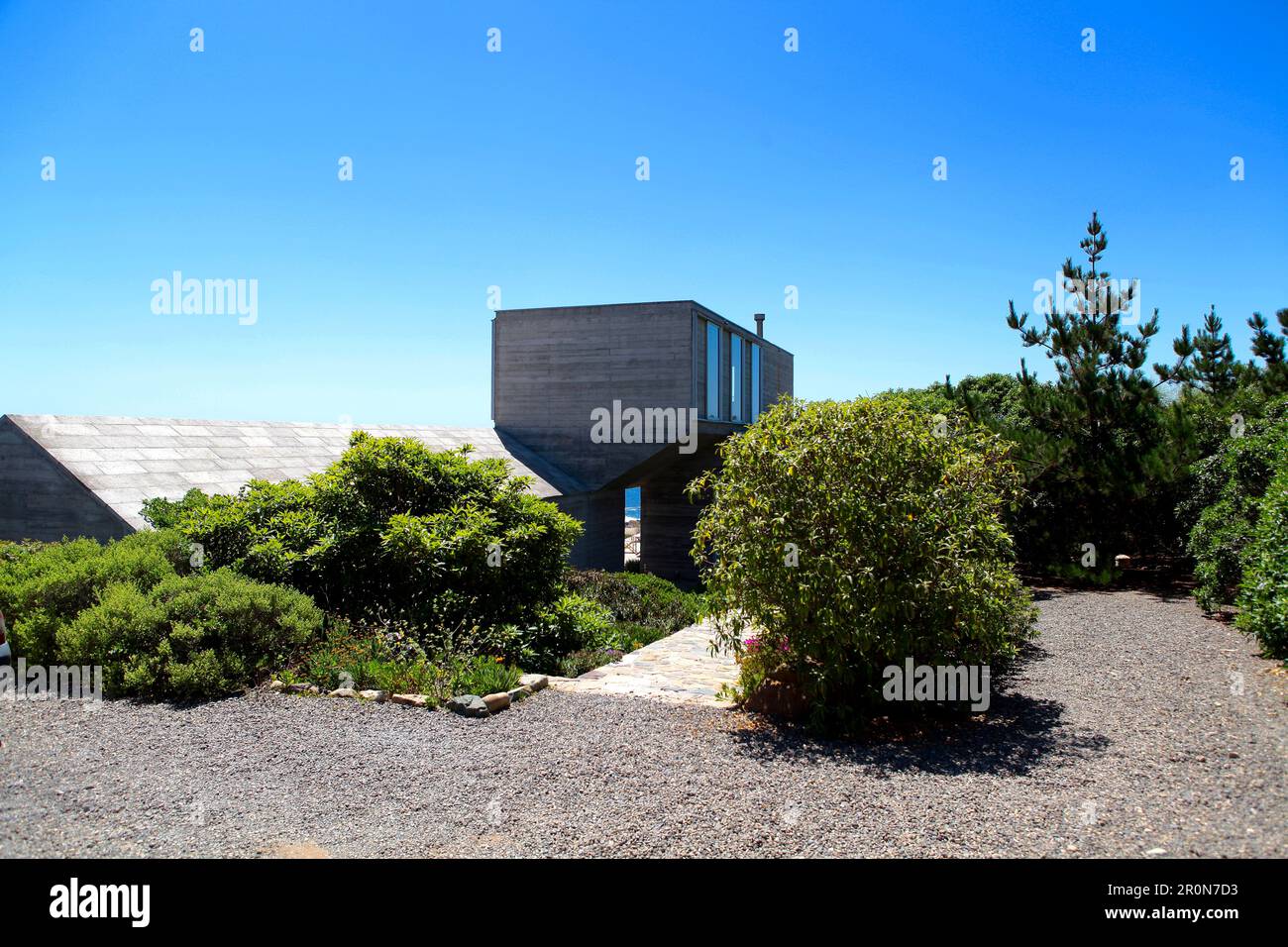 A modern, concrete house perched atop a lush, grassy landscape Stock ...