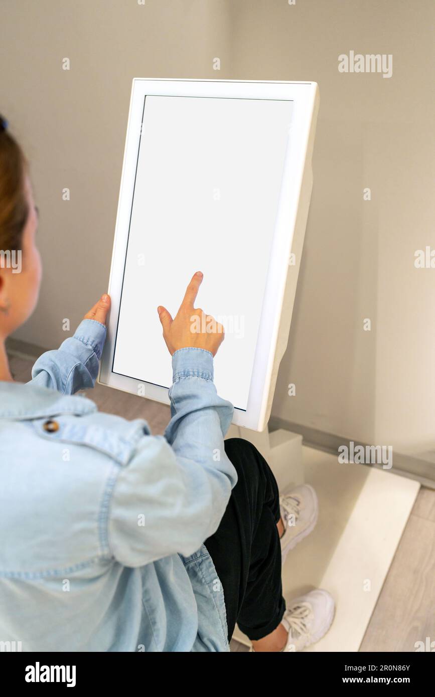 Woman using big digital touch screen in public place, navigation, check ...