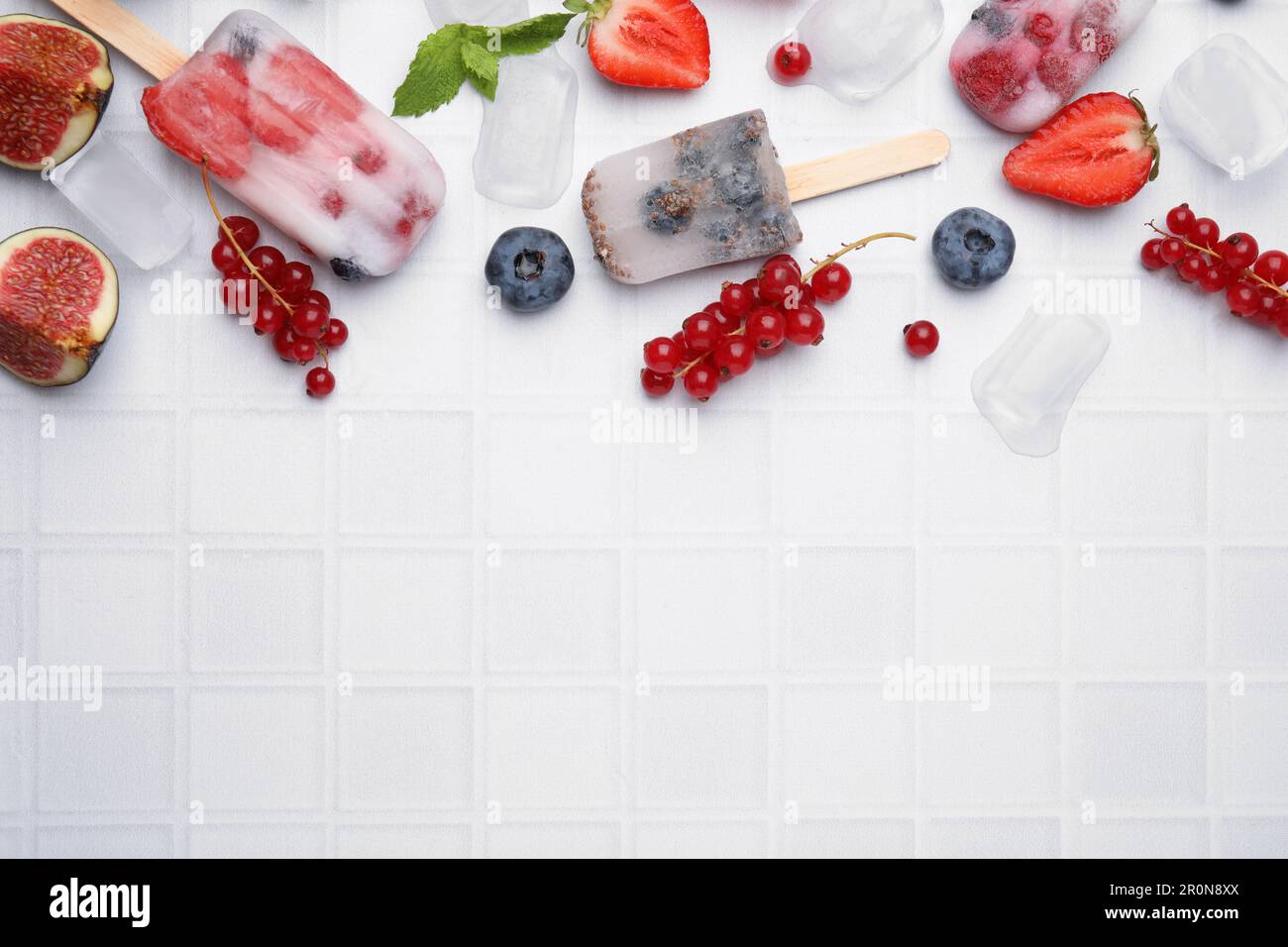 Flat lay composition with berry ice pops on white table. Space for text ...