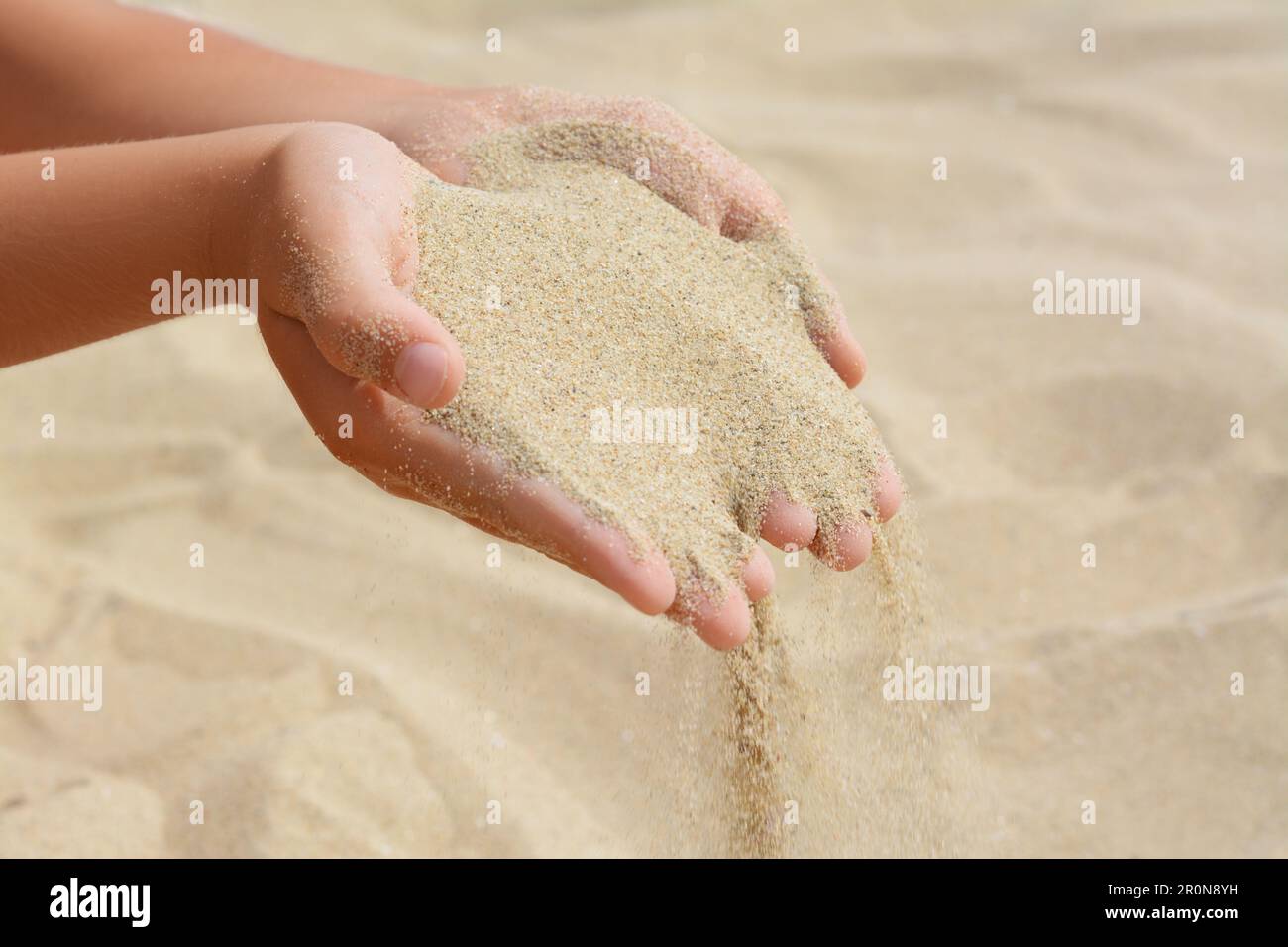 Child pouring sand from hands on beach, closeup. Fleeting time concept ...
