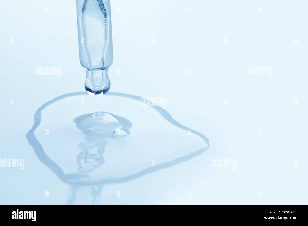 Dripping face serum from pipette on white background, closeup. Space ...